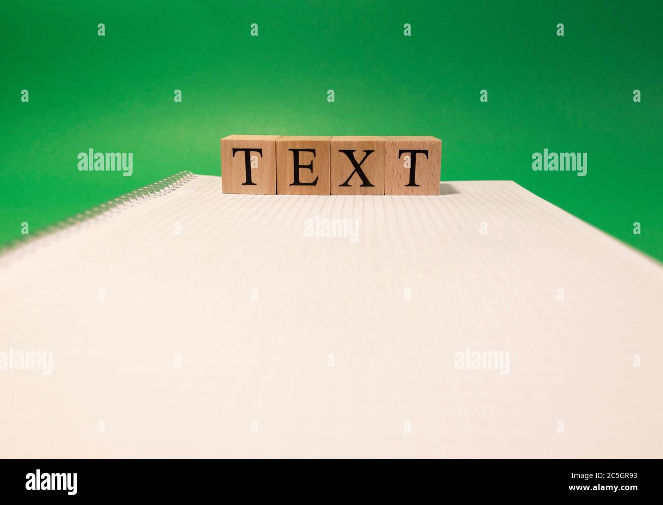 Text writing from wooden cubes. Under notepad and green background ...