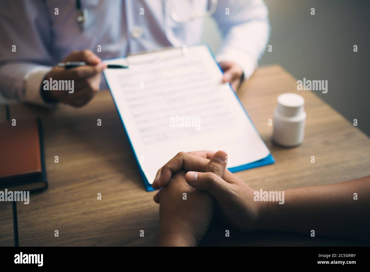 Doctor hand holding pen pointing patient history list on note pad and ...