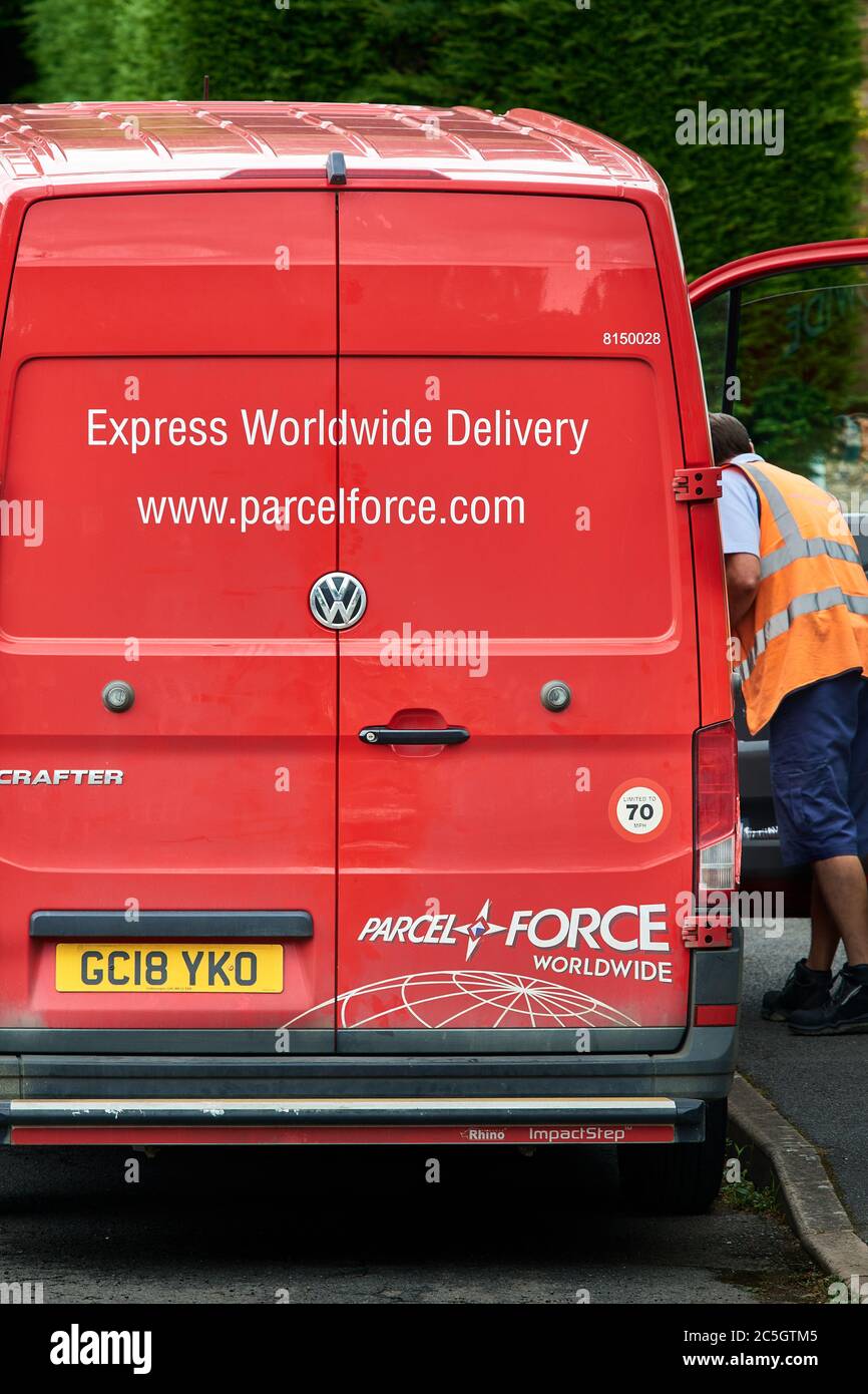 A red Parcel Force van parked on a street as the driver prepares to ...