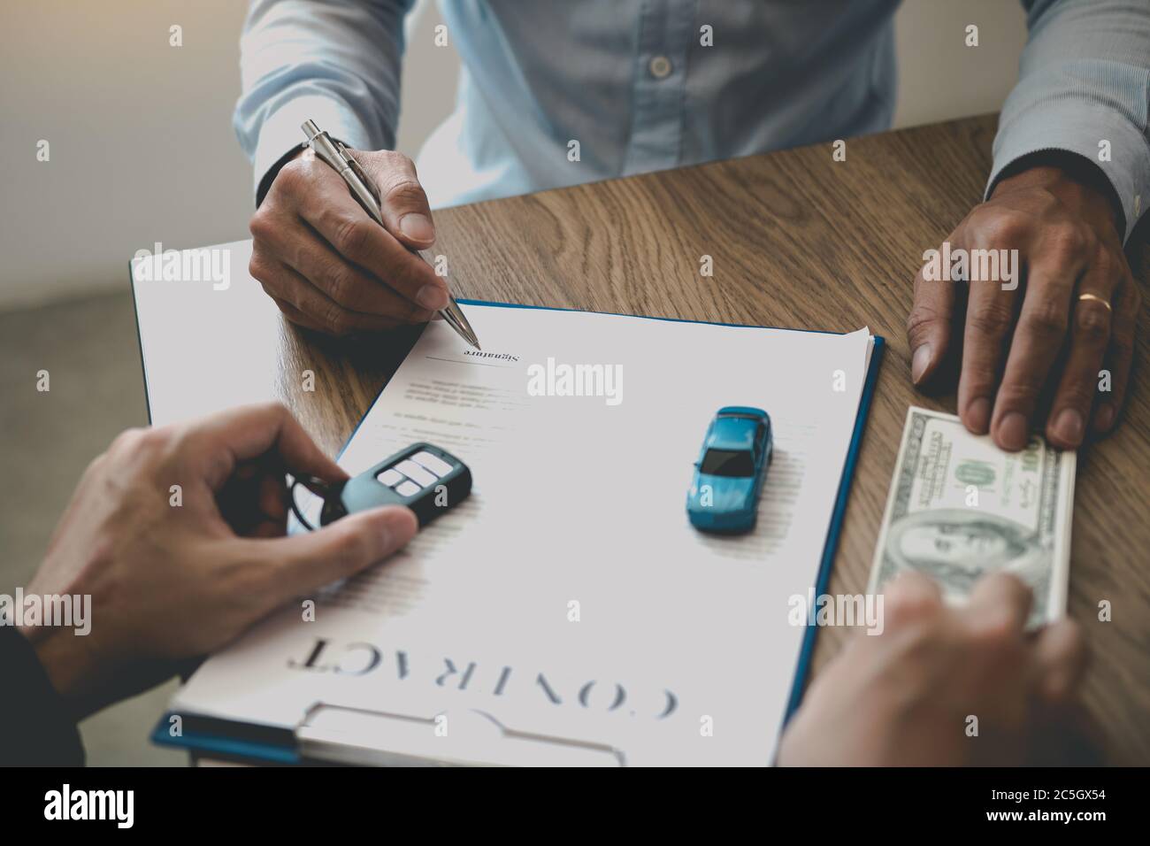 New car buyers are signing a contract with a car salesman at the ...