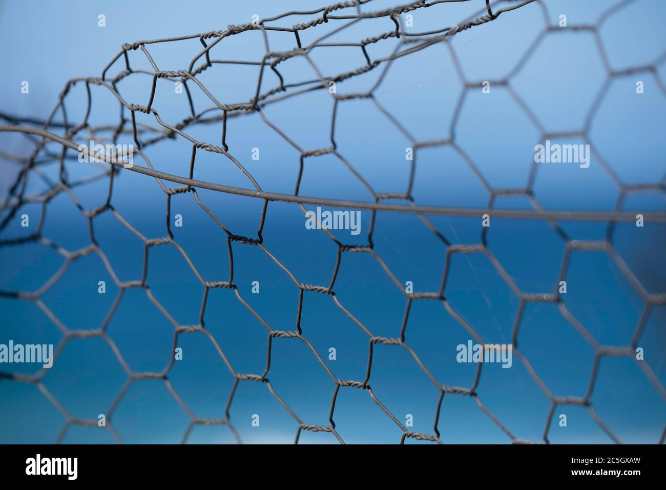 Broken wire mesh fence against blue sky and sea Stock Photo - Alamy
