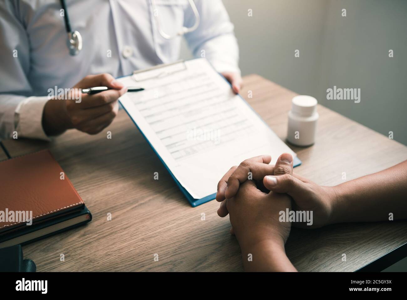 Doctor hand holding pen pointing patient history list on note pad and ...