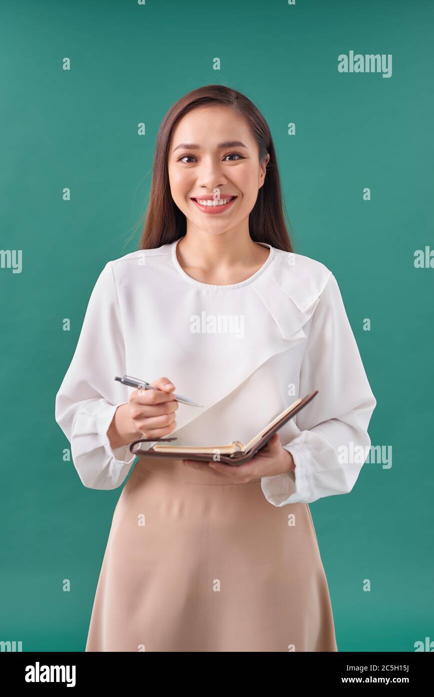 Pretty young beautiful woman standing, writing, take notes, holding ...