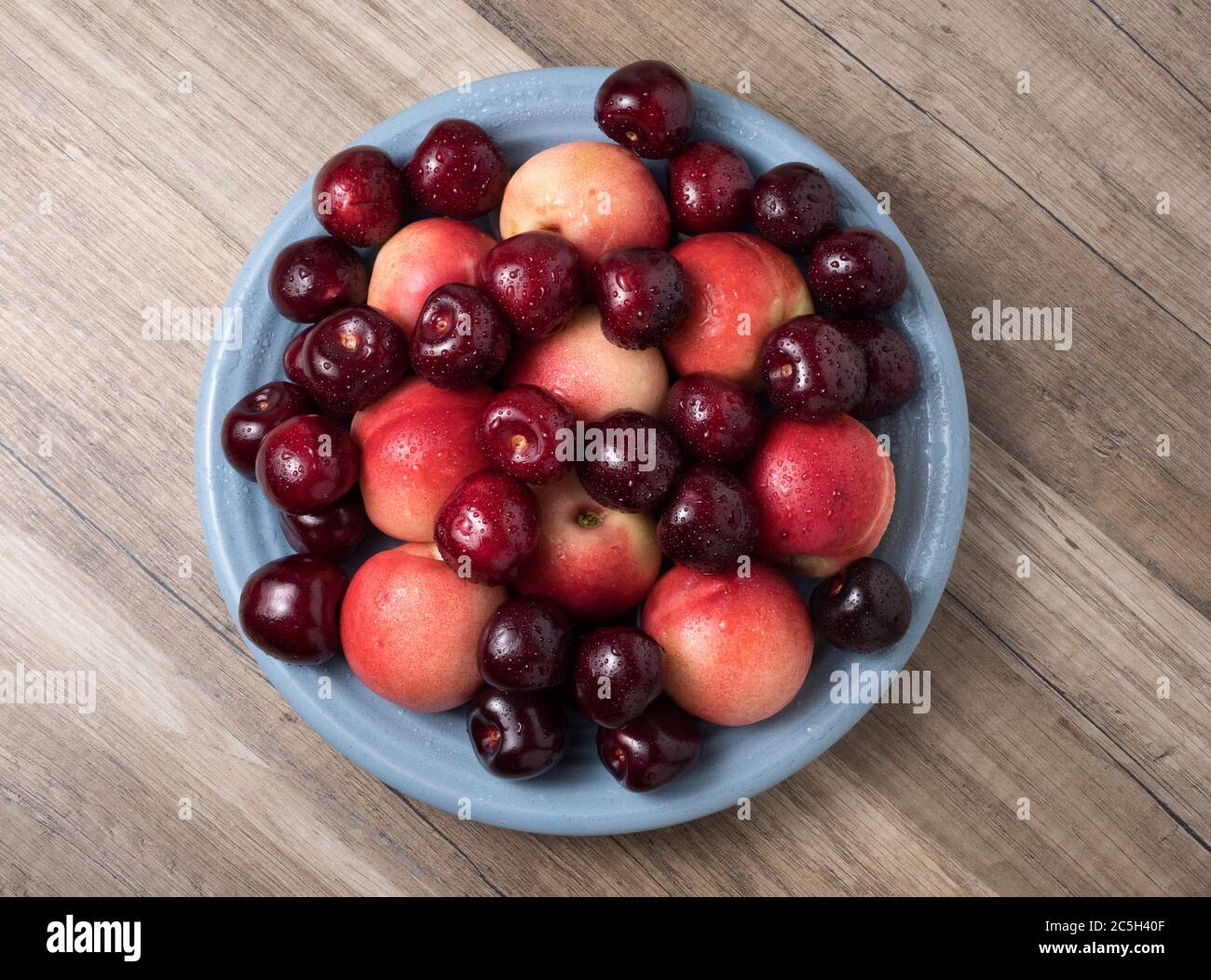 Sweet cherries and ripe juicy nectarines in a dish, on wooden ...
