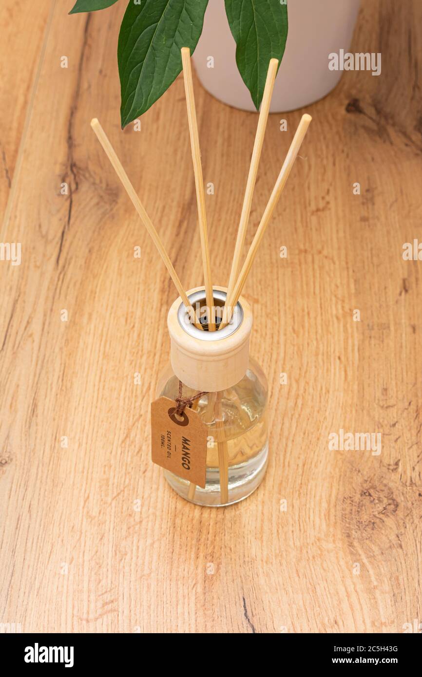 Aroma reed diffuser in the interior. Red rose flowers in vase on wooden ...