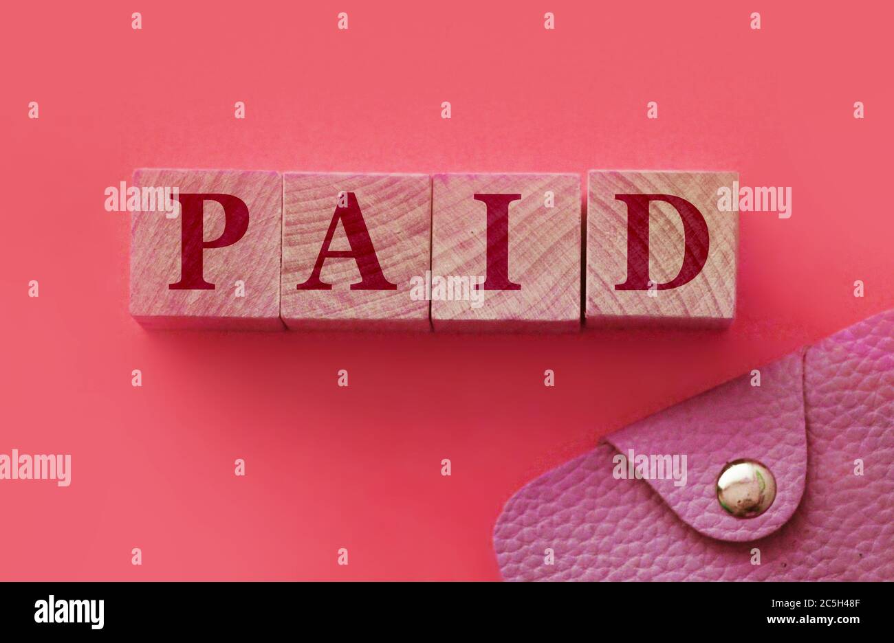 Paid word from wooden blocks and pink wallet on pink background. Taxes ...