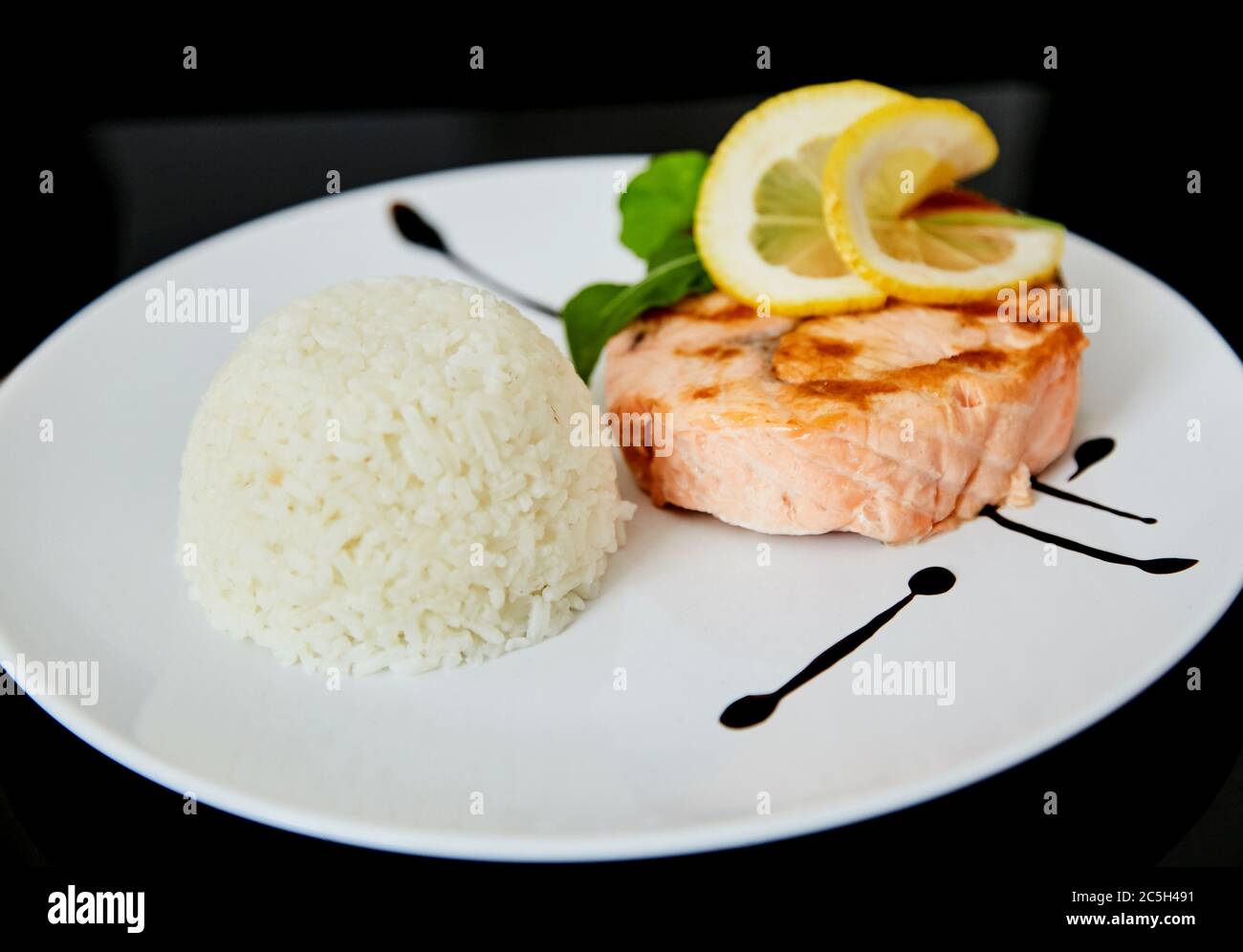 Fish fillet with rice. Dish on black background Stock Photo - Alamy