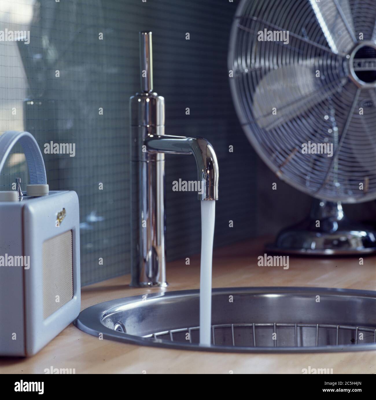 Chrome tap full on with water gushing into round sink Stock Photo - Alamy