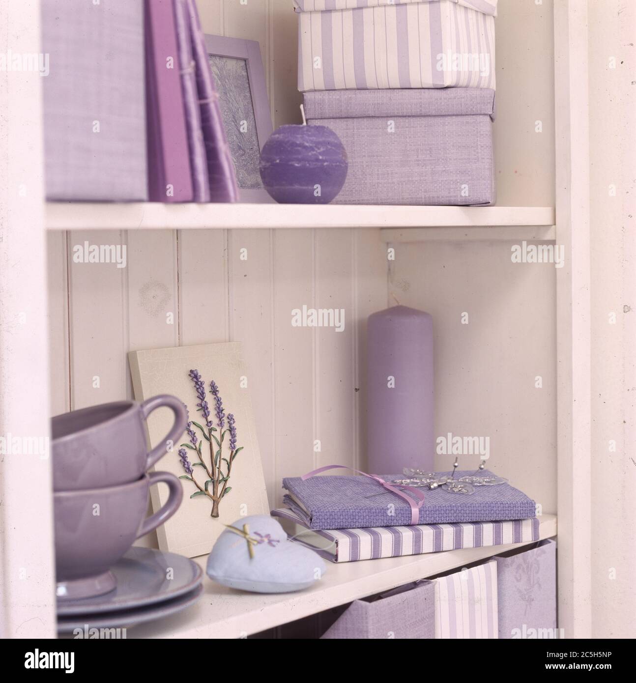 Crockert and various mauve coloured objects on white painted shelves ...