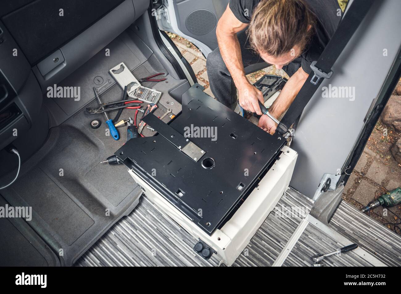 Man installing a swivel seat base in his camper van Stock Photo - Alamy