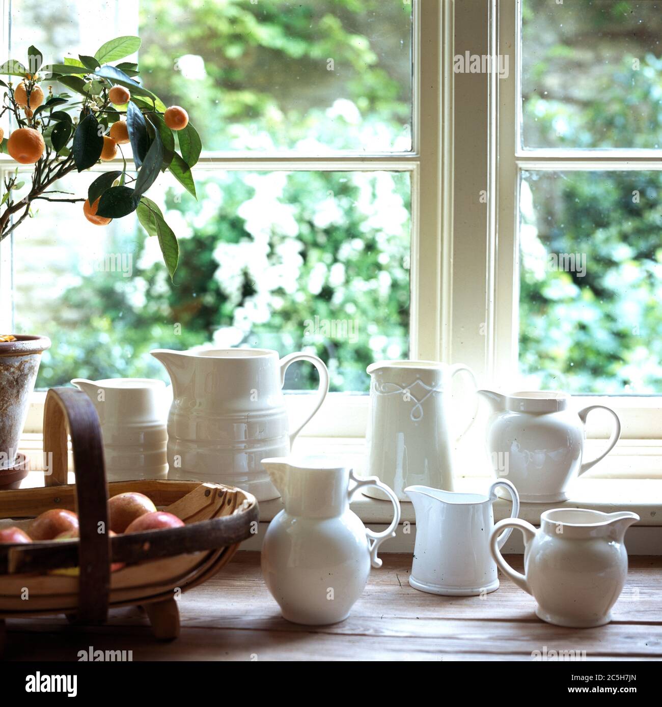 Window ledge with collection of white jugs and basket of fruit Stock ...