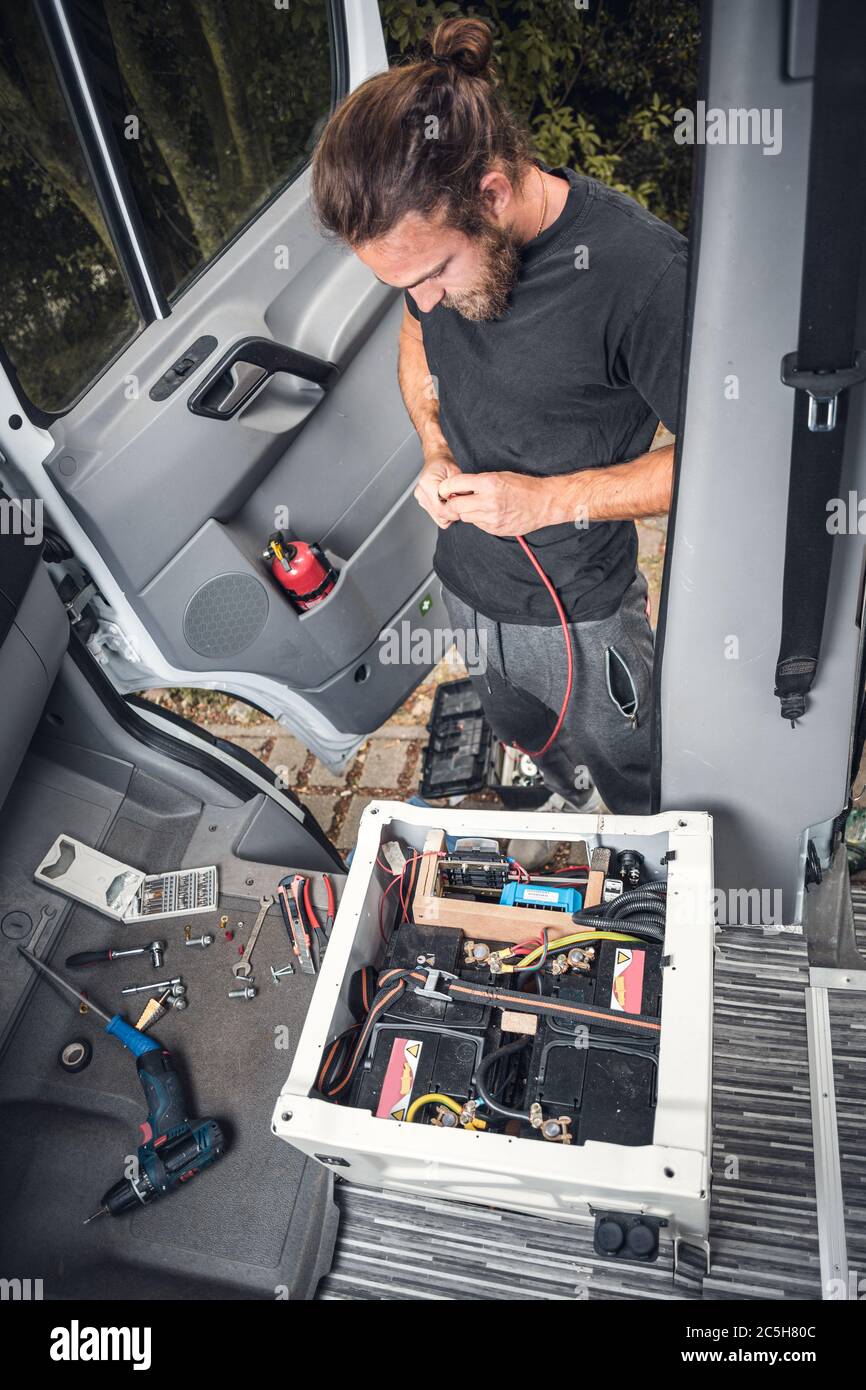 Man installing electronics in his DIY camper van Stock Photo - Alamy