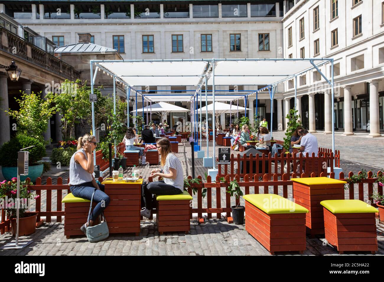 People sit in Covent Garden piazza having lunch in social distanced ...