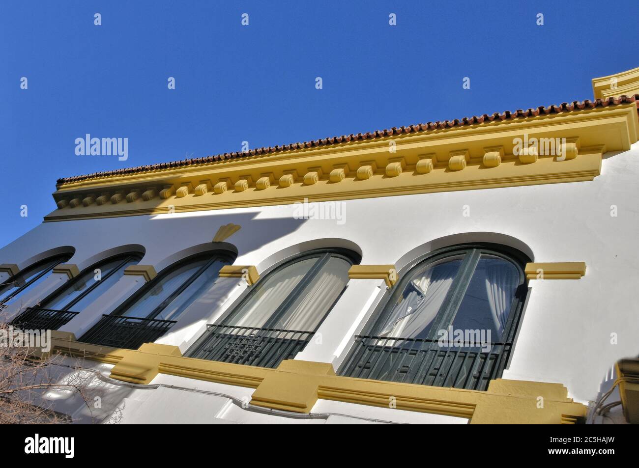 White Andalusian building with windows and eaves and blue sky in ...