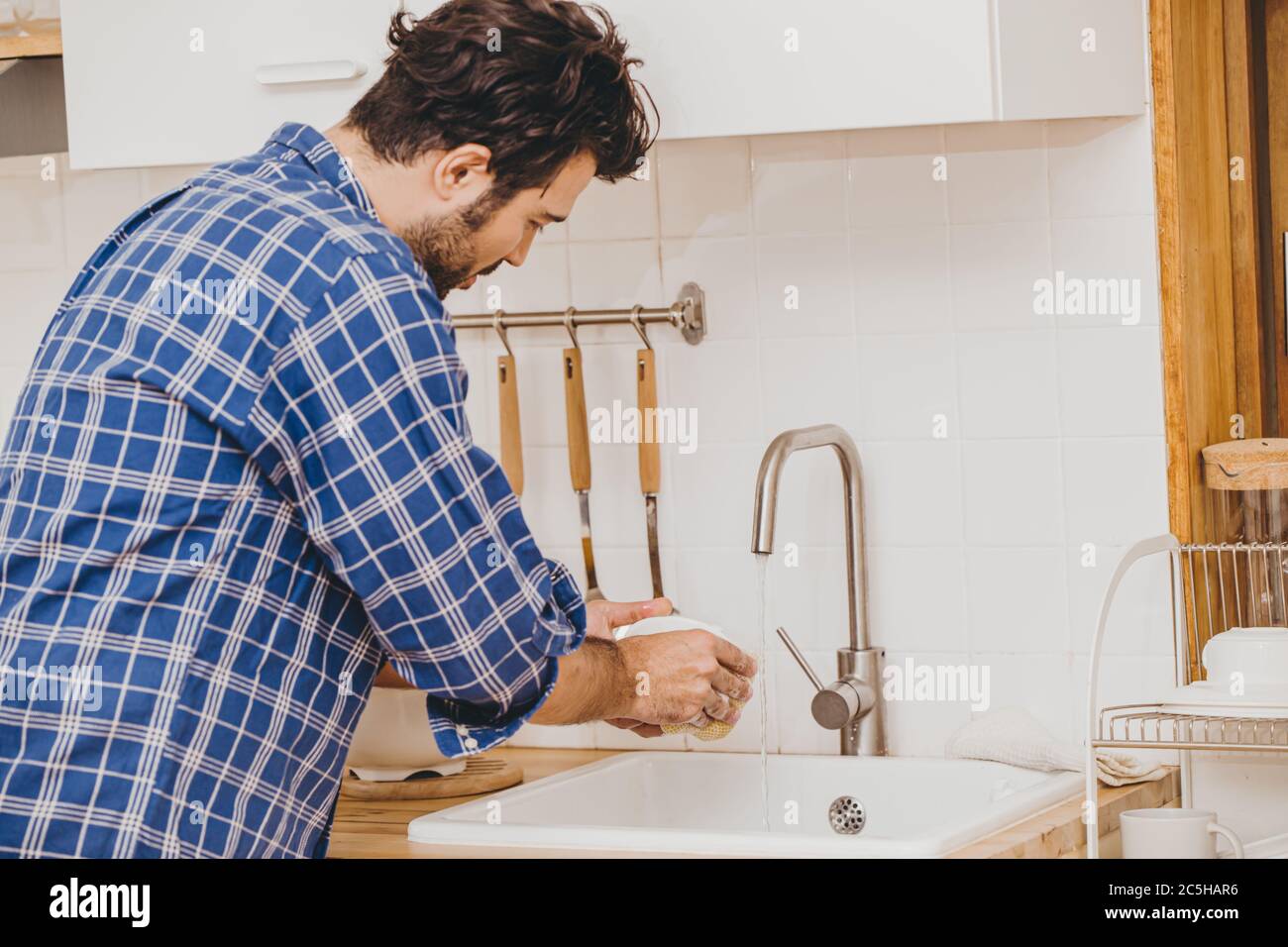 Man widower doing chores or house work alone cleaning wash dishes in ...