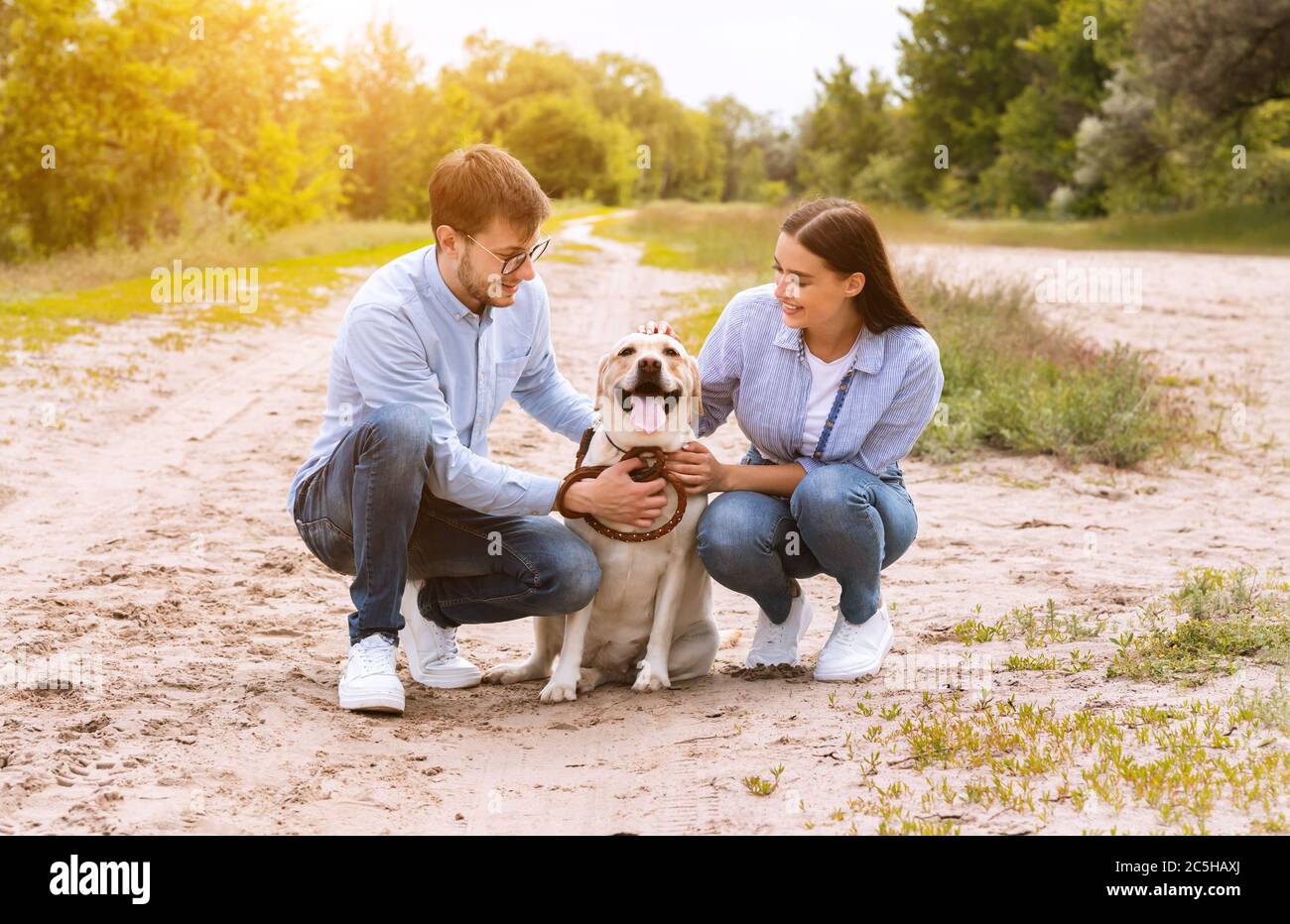 Portrait of happy young couple hugging their cute dog Stock Photo - Alamy
