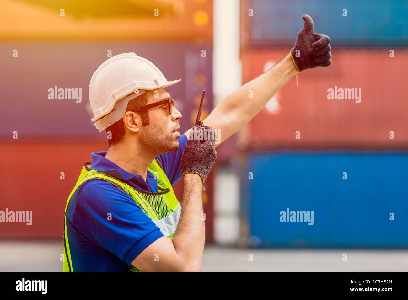 Foreman shipping staff worker working radio control loading cargo port ...