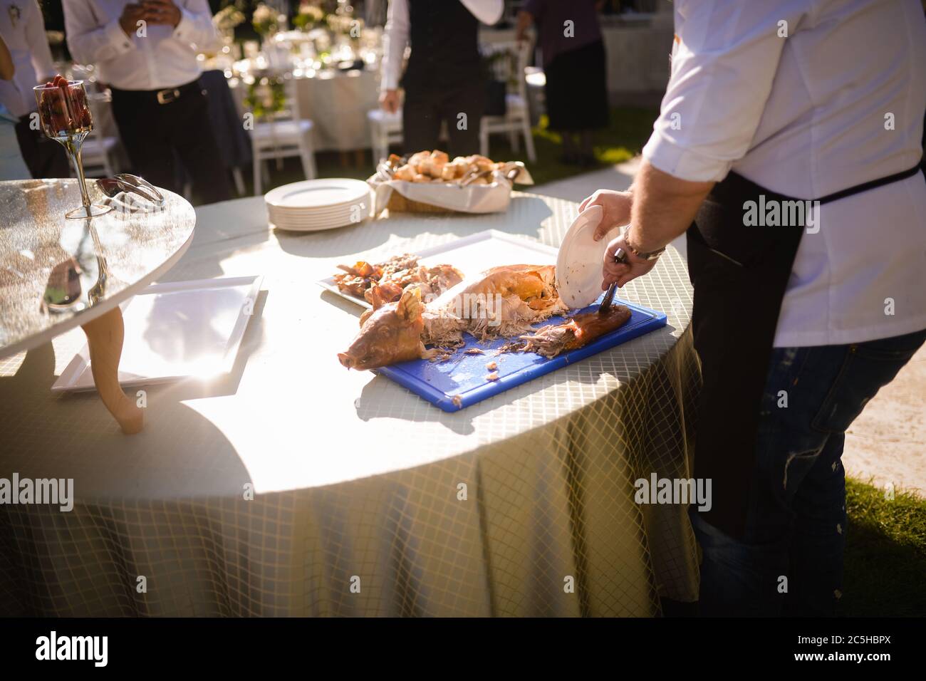 The waiter serves the roast pig on an oval at an outdoor party Stock ...