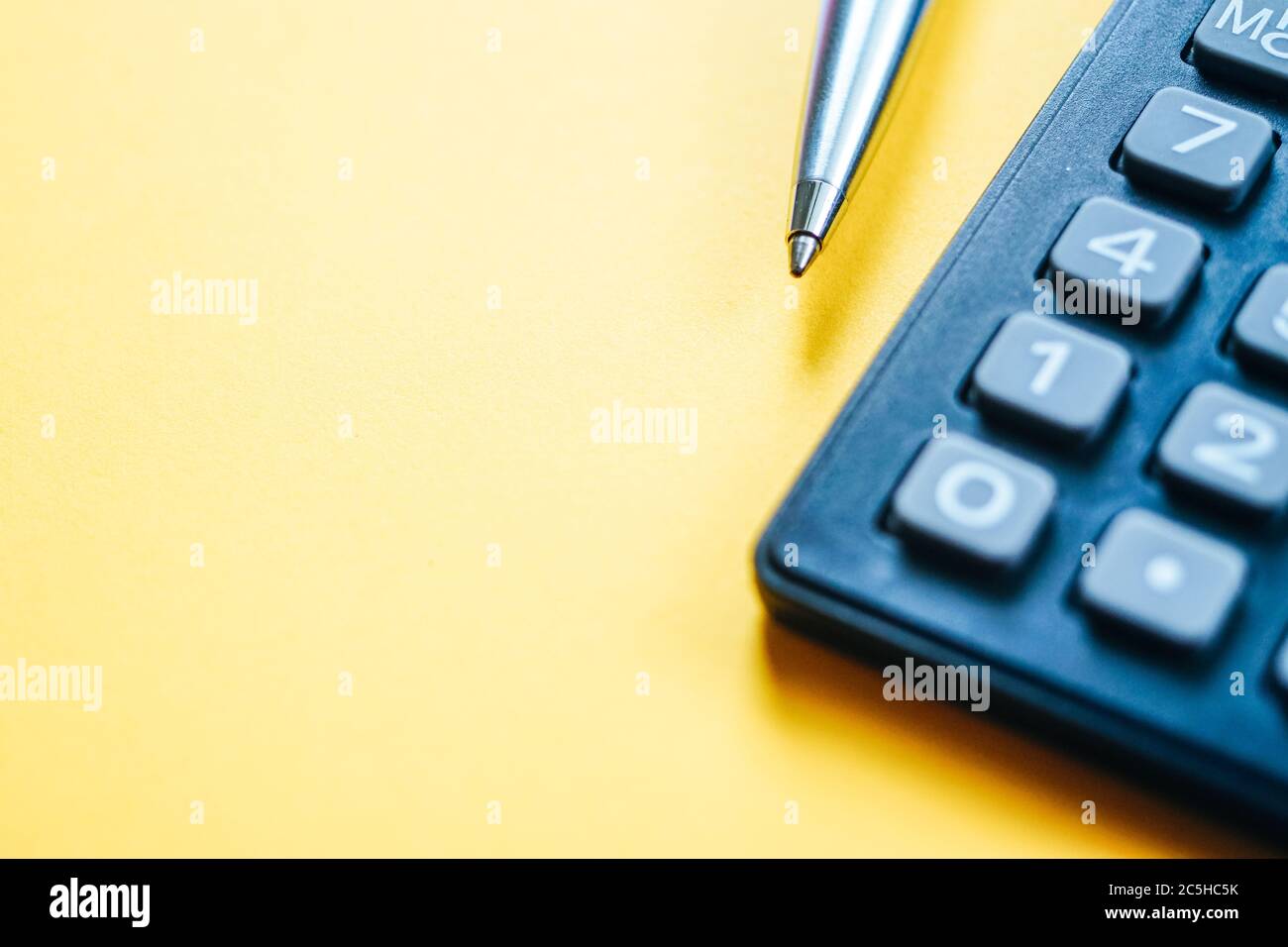 Close up a calculator and a pen over yellow background. Financial ...