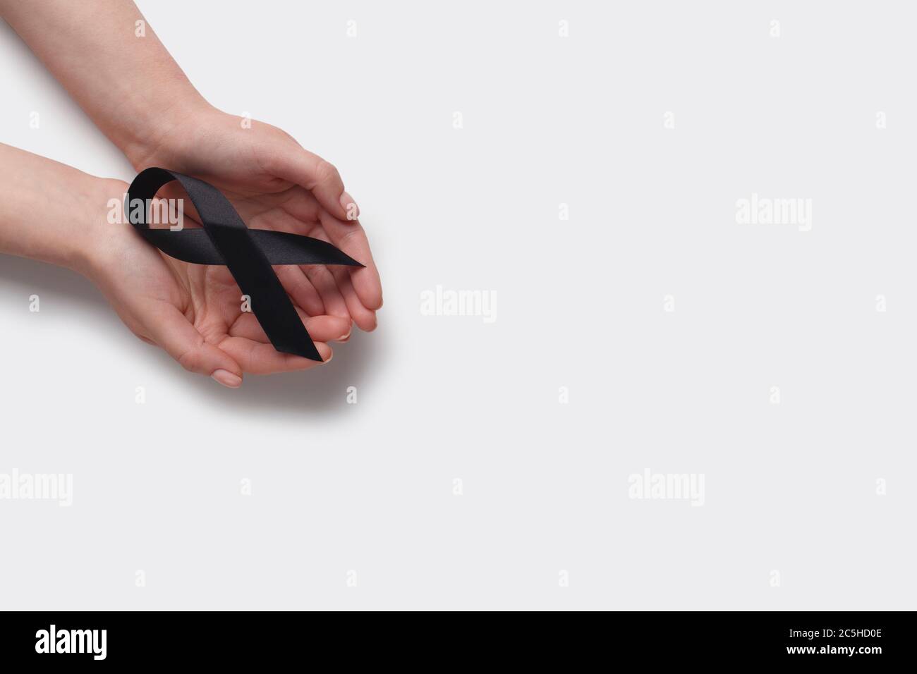 Black awareness ribbon in hands on white background Stock Photo - Alamy