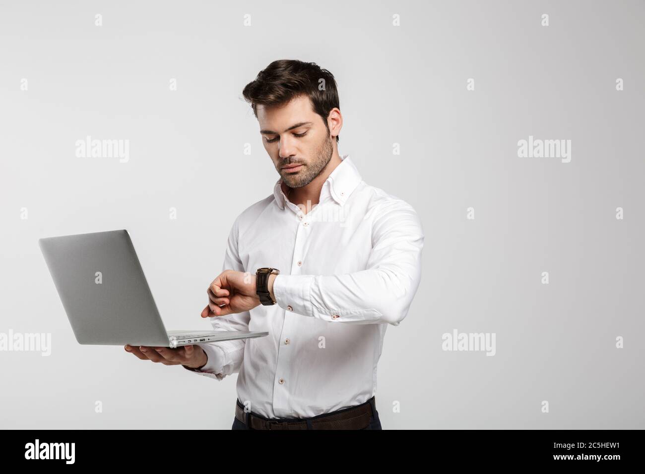 Image of young successful businessman holding laptop and looking at ...