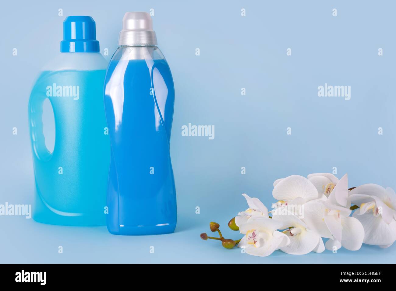 Bottles of detergent and fabric softener with orchid flowers on blue ...