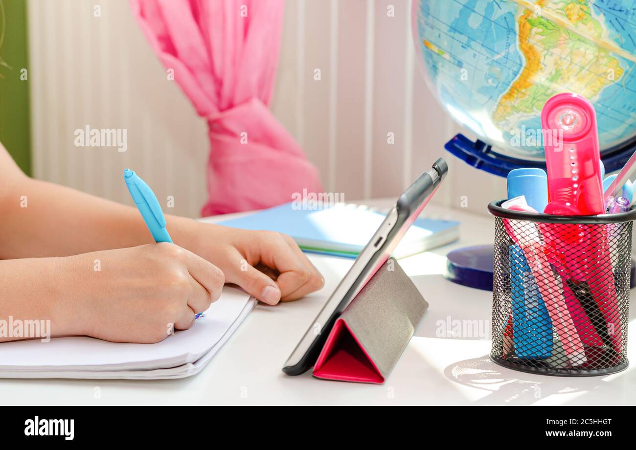 Hands of a child writing homework with tablet and stationery on white ...