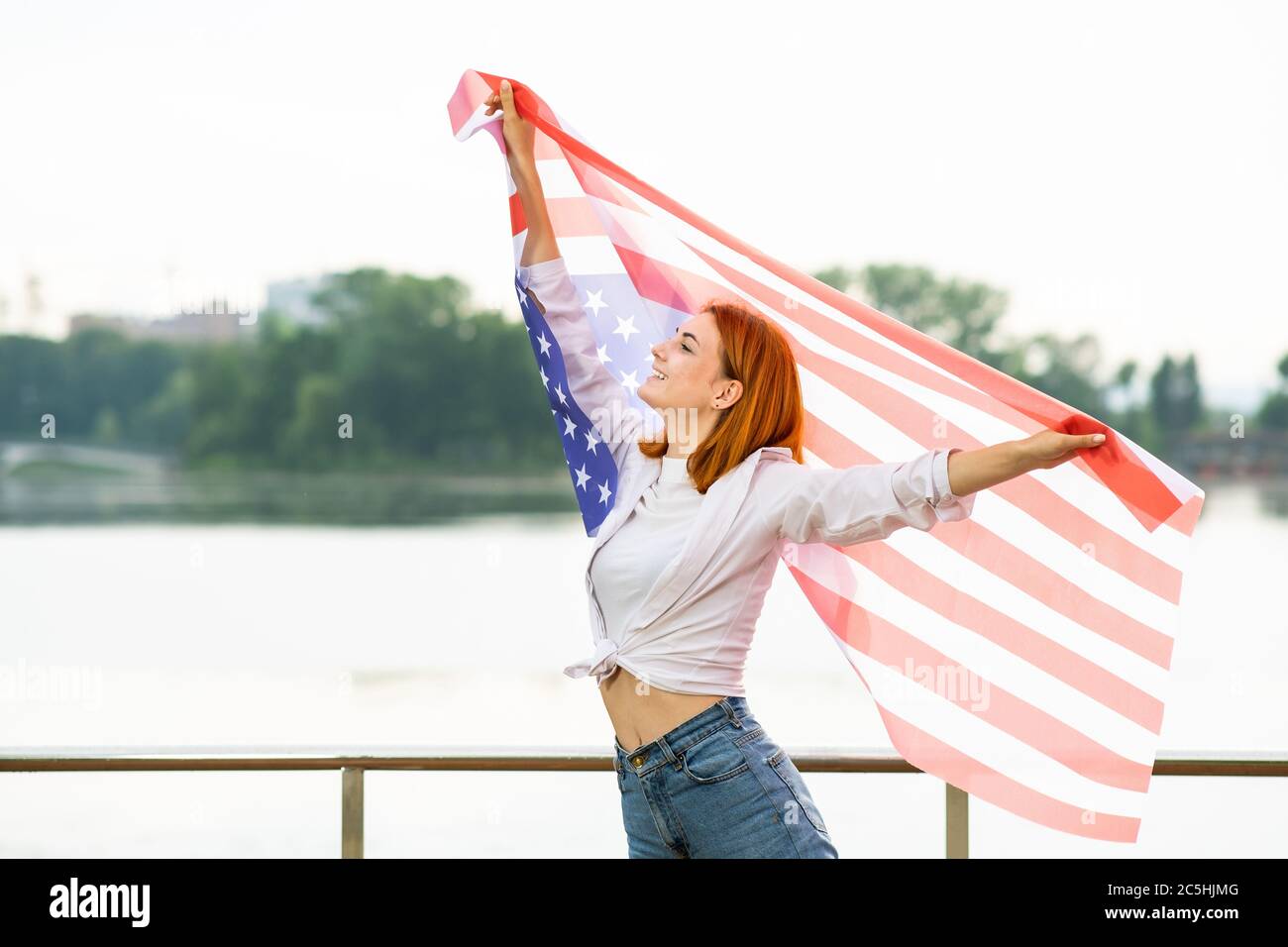 Portrait of happy smiling red haired girl with USA national flag in her ...