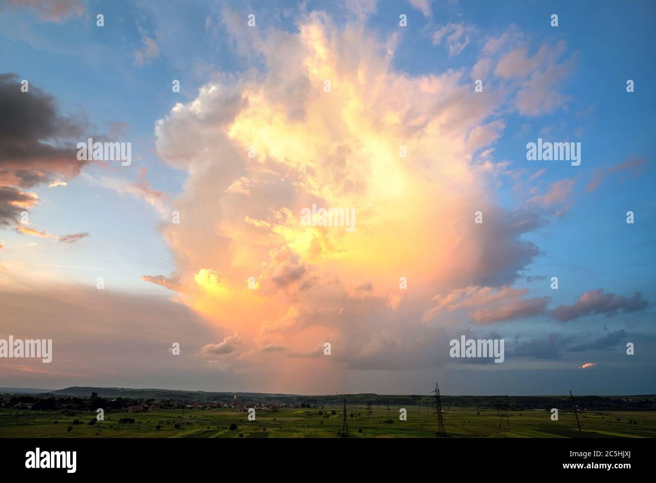 Dramatic stormy sunset over rural area with puffy clouds lit by orange ...