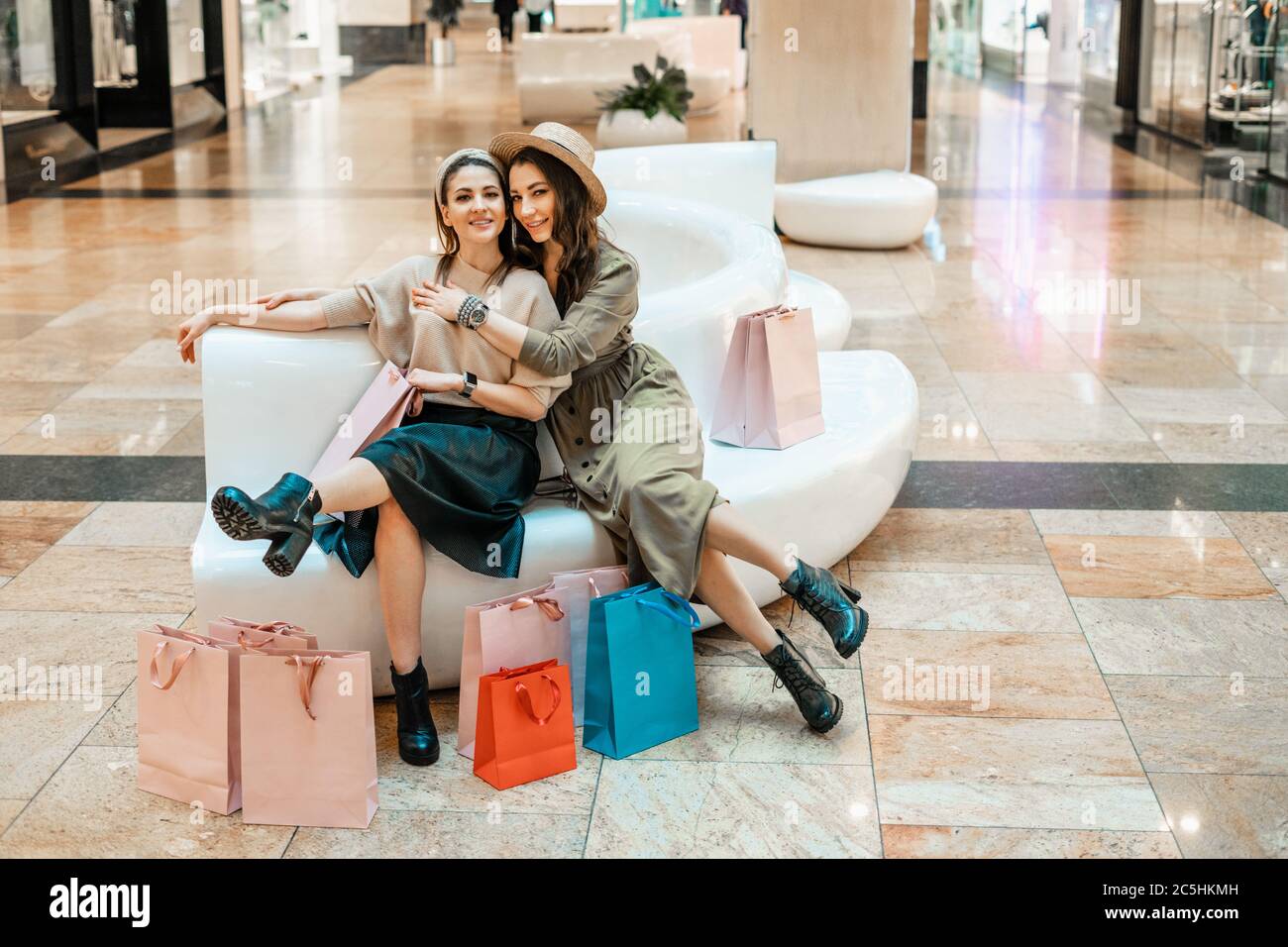 Girls are resting on the couch in the mall. Shopping, entertainment and ...