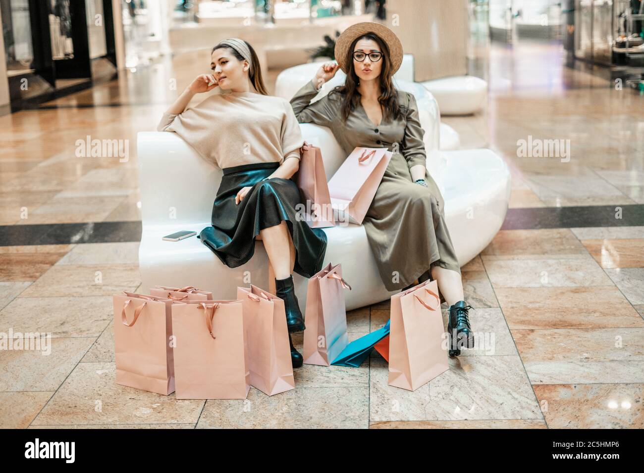 Girls are resting on the couch in the mall. Shopping, entertainment and ...