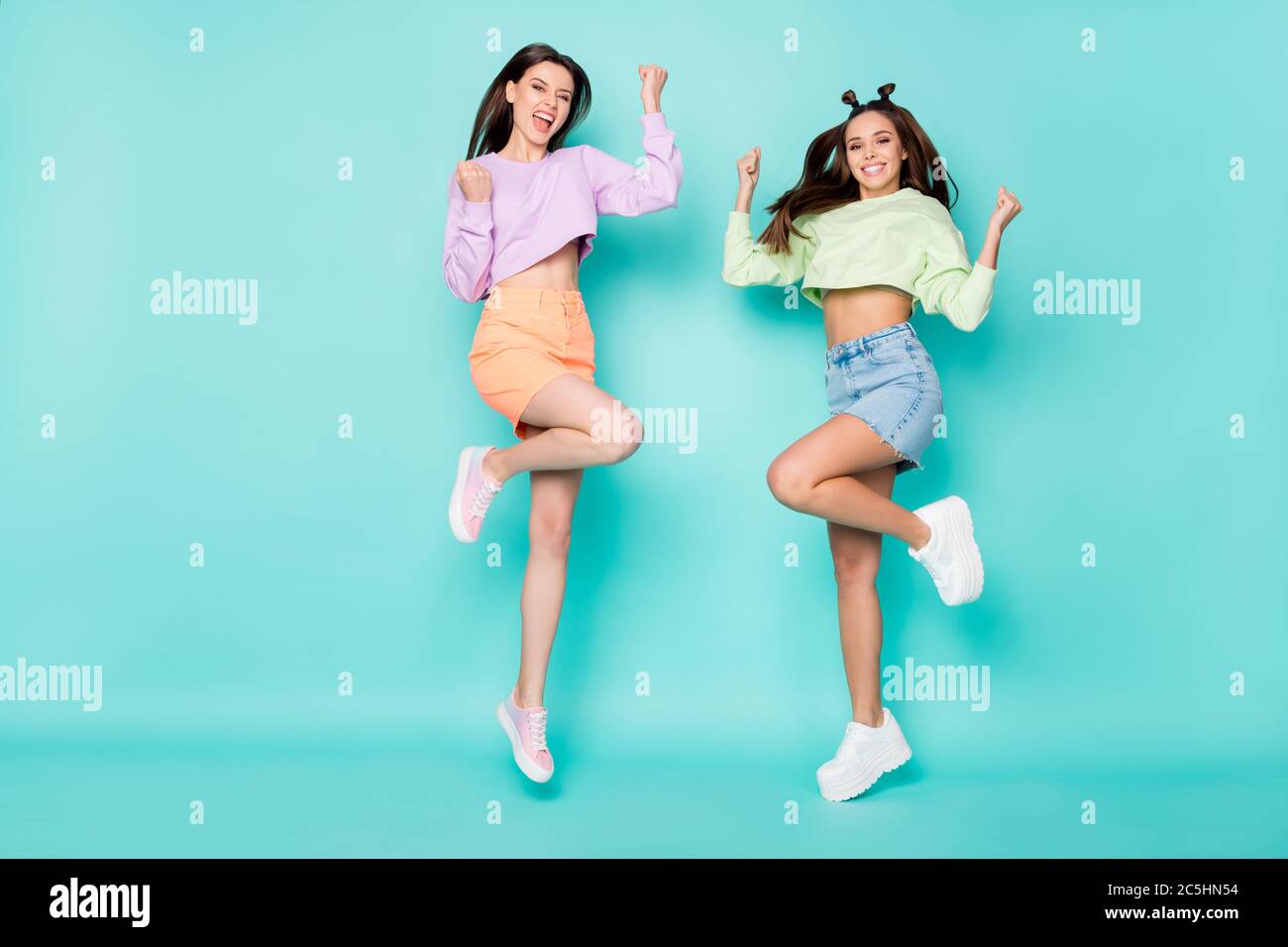 Full length photo of two pretty lady best friends jump high youth ...