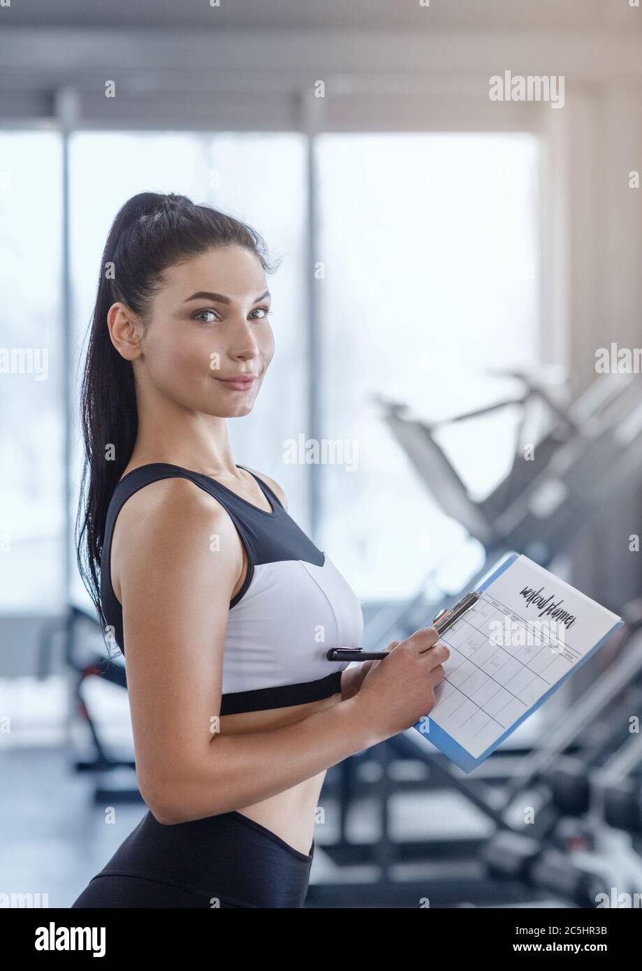 Attractive personal trainer composing workout schedule for client at ...