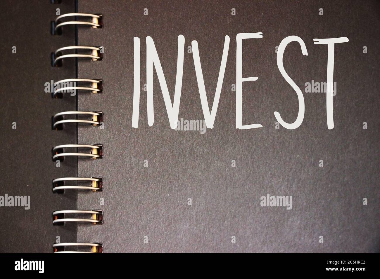 Invest text on spiral copybook page. Saving and spending concept ...