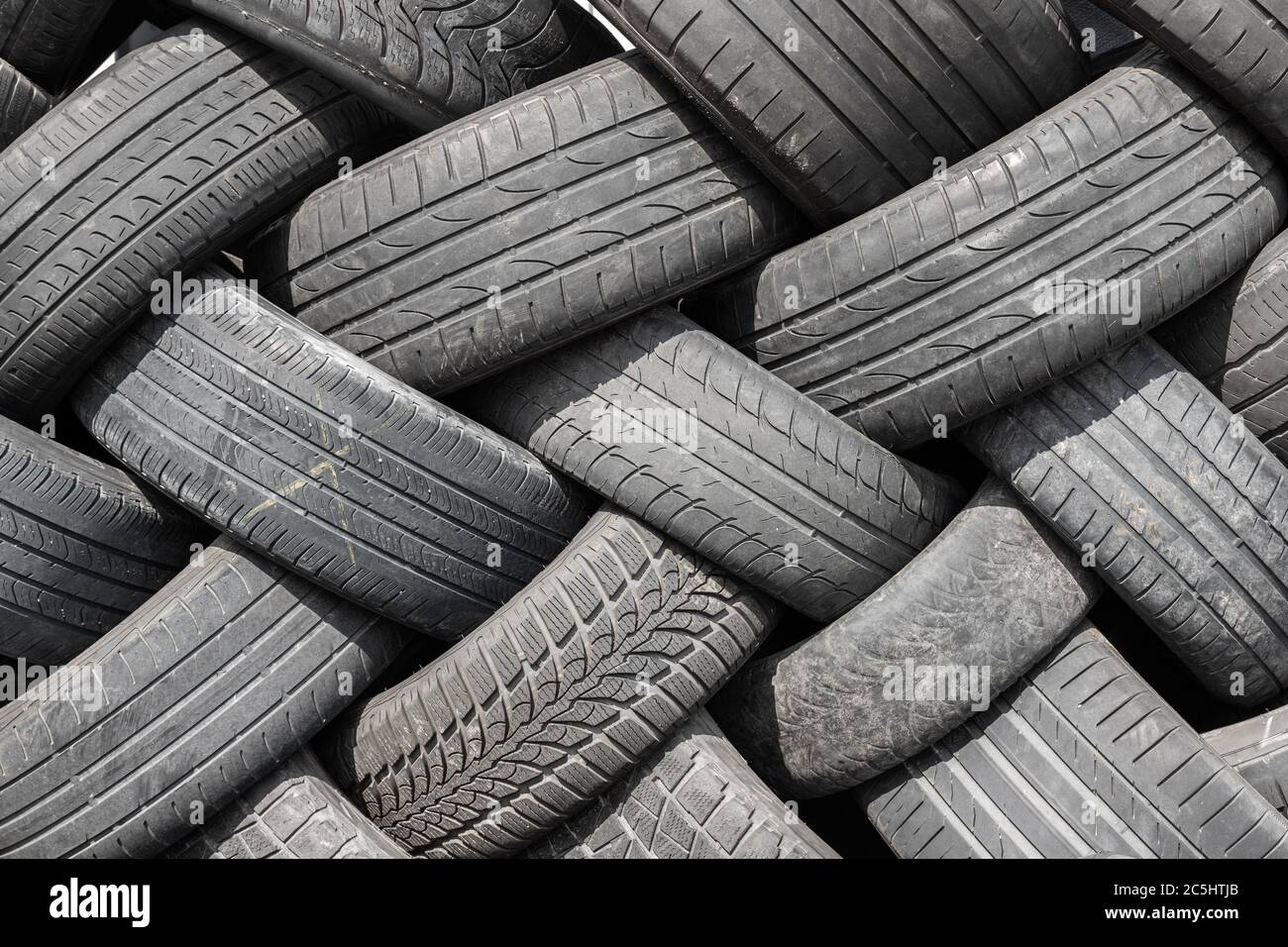 Old used weared car and truck wheels tyres pile stacked in rows stored ...