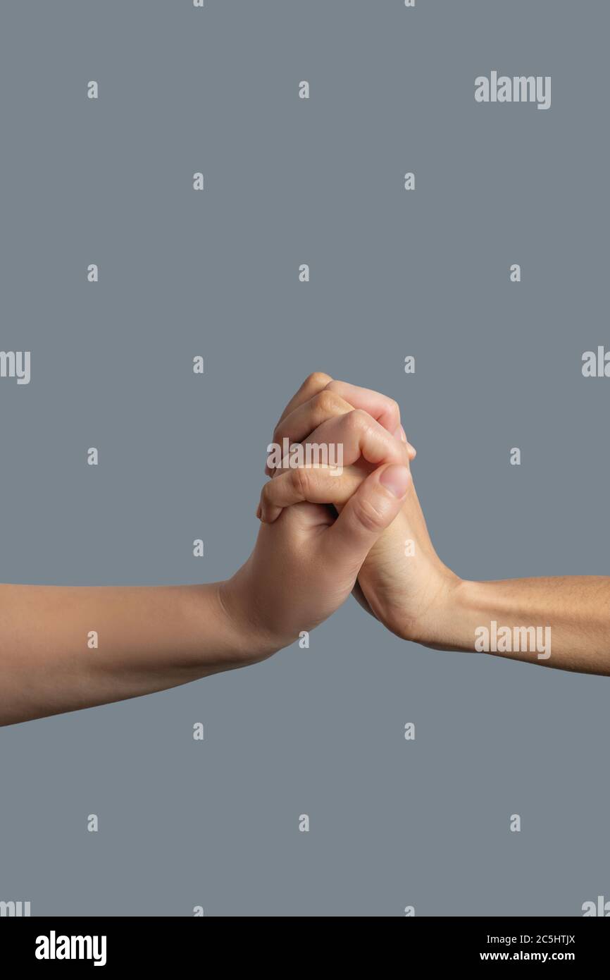 Close-up of fair-skinned and dark-skinned hands clenched together Stock ...