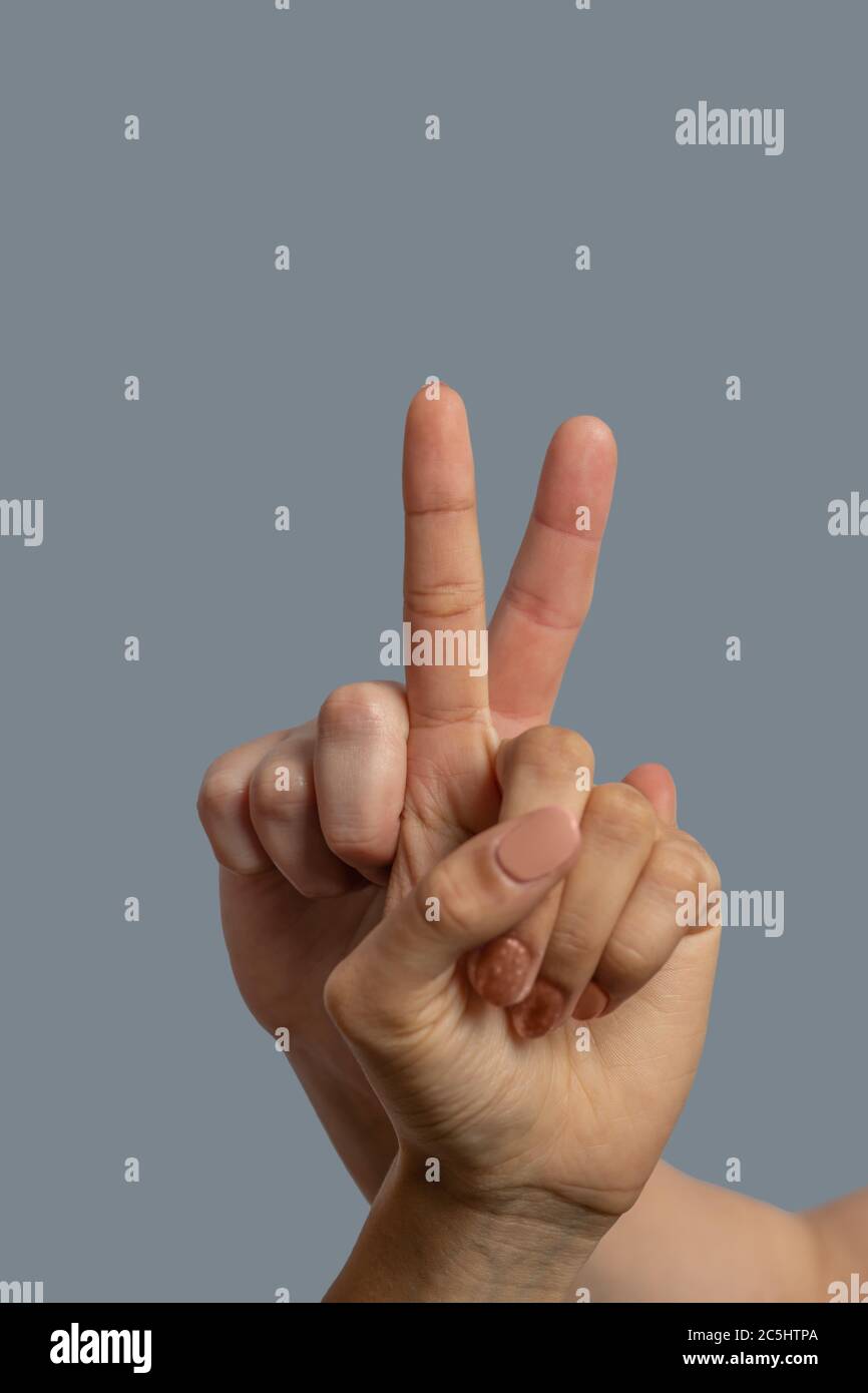 Close-up of light-skinned and dark-skinned hands showing peace gesture ...