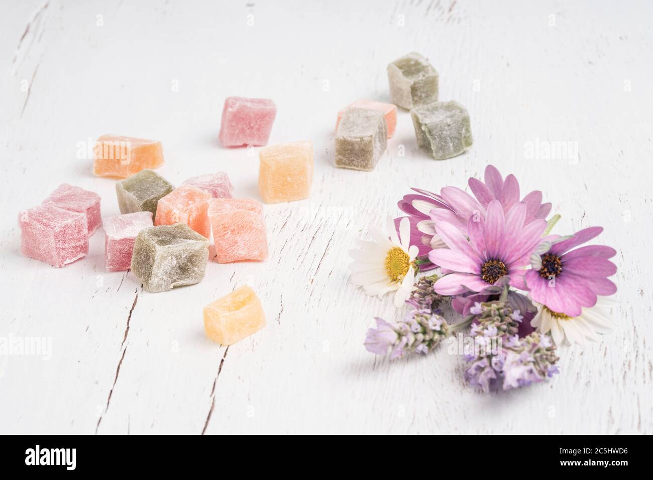 colorful Turkish delights and spring flowers on a wooden table with ...