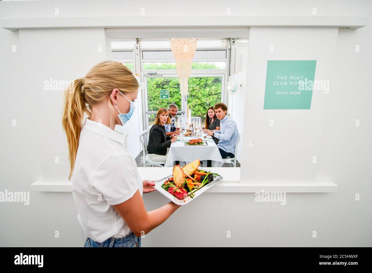 A server brings food through a hatch to diners in family bubbles to ...