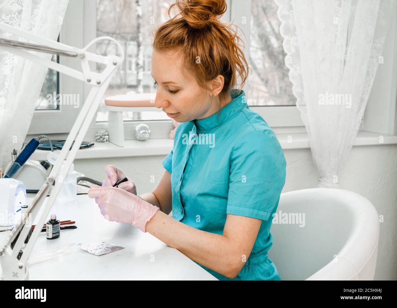 Manicurist at work in the office. Drawing gel polish on tips, creating ...