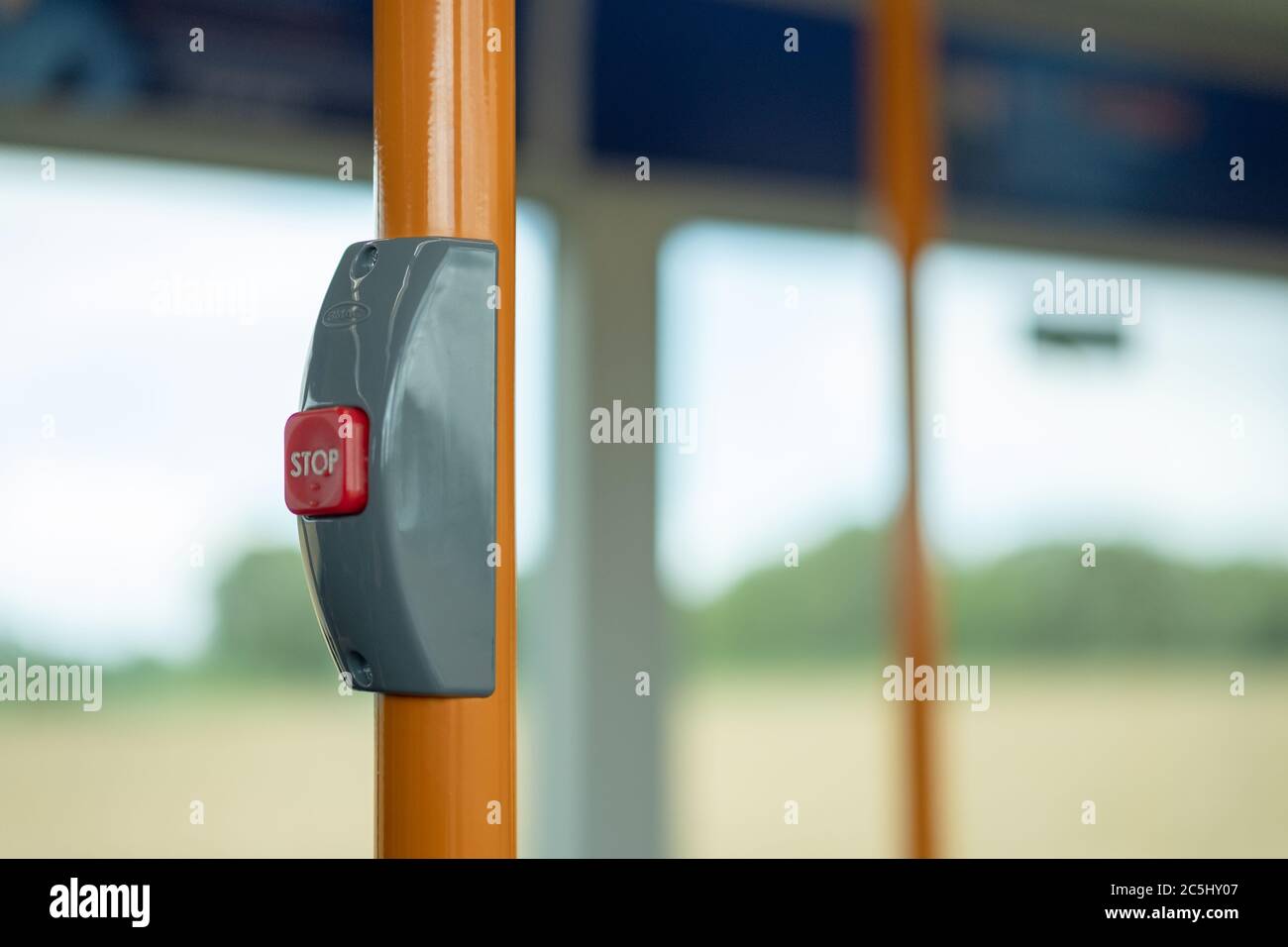 Shallow focus of a red stop button seen inside a public bus. Used to ...