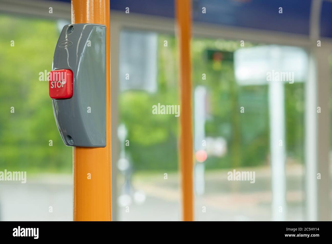 Shallow focus of a red stop button seen inside a public bus. Used to ...