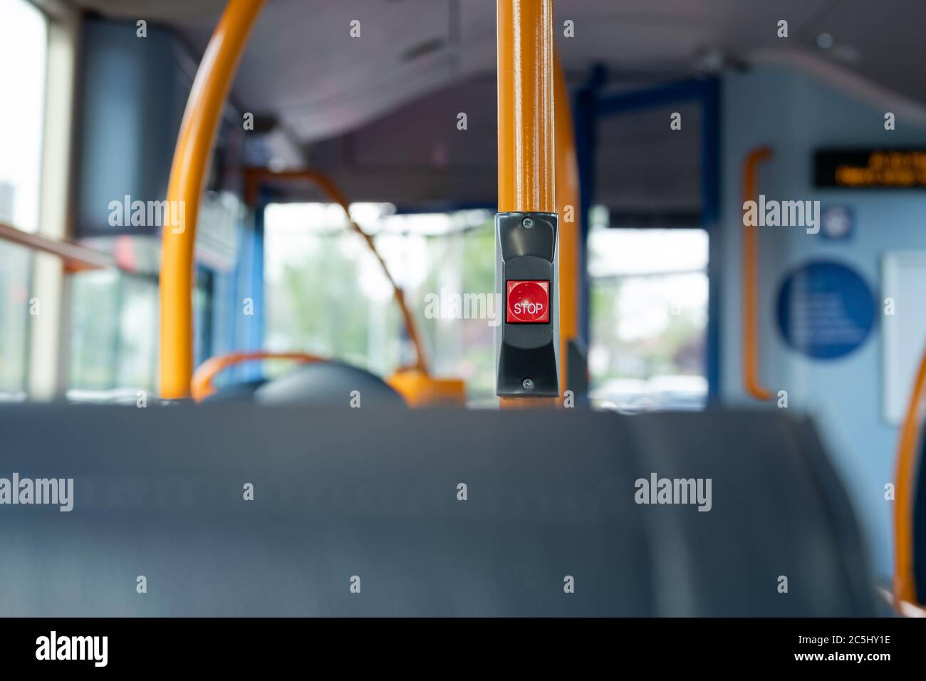 Shallow focus of a red stop button seen inside a public bus. Used to ...