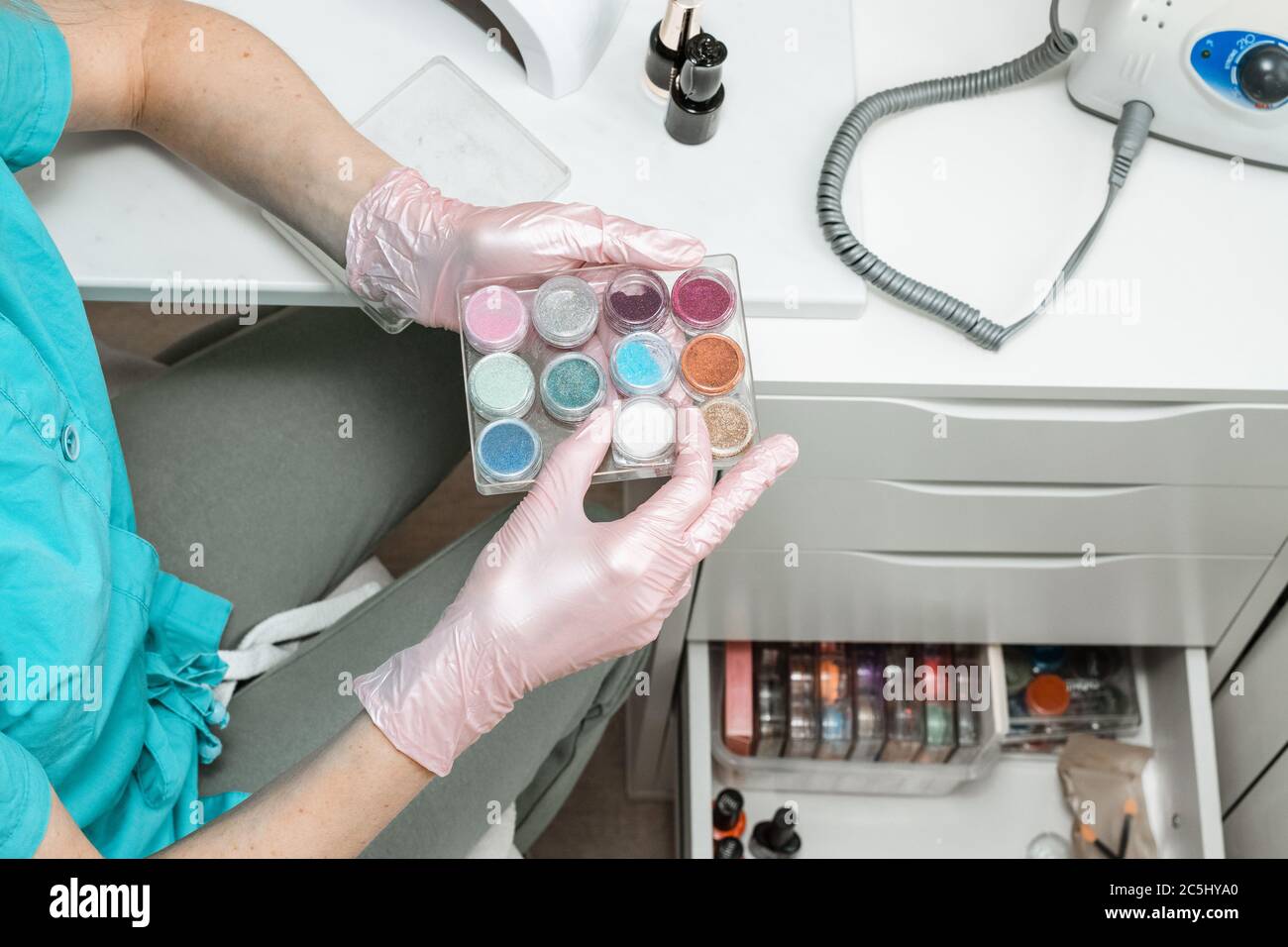 Manicurist at work in the office. Drawing gel polish on tips, creating ...