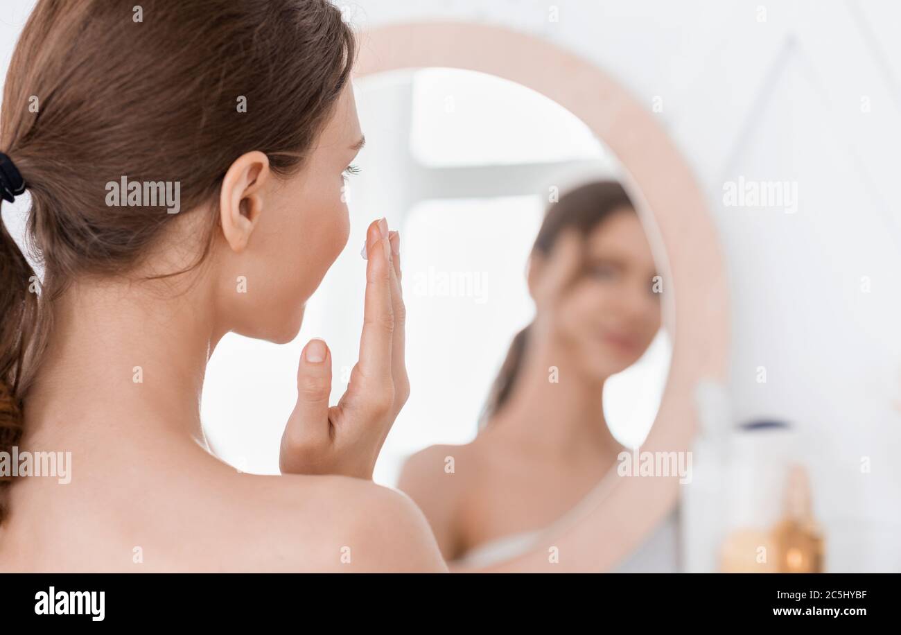 Back view of young woman looking at mirror Stock Photo - Alamy