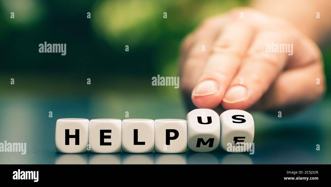 Hand turns dice and changes the expression "help me" to "help us Stock ...