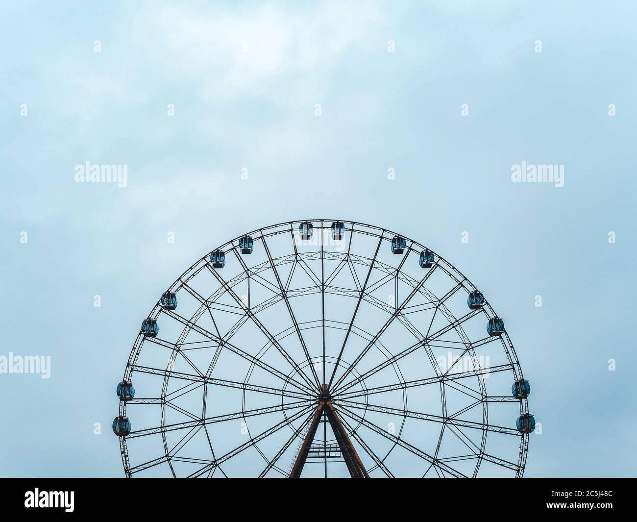 High modern ferris wheel with closed booths on a background of blue sky ...