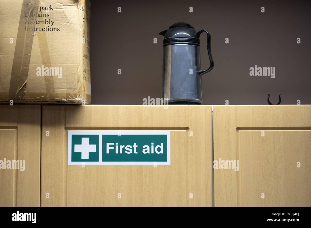 First Aid sign located on an office kitchen cupboard, containing a ...