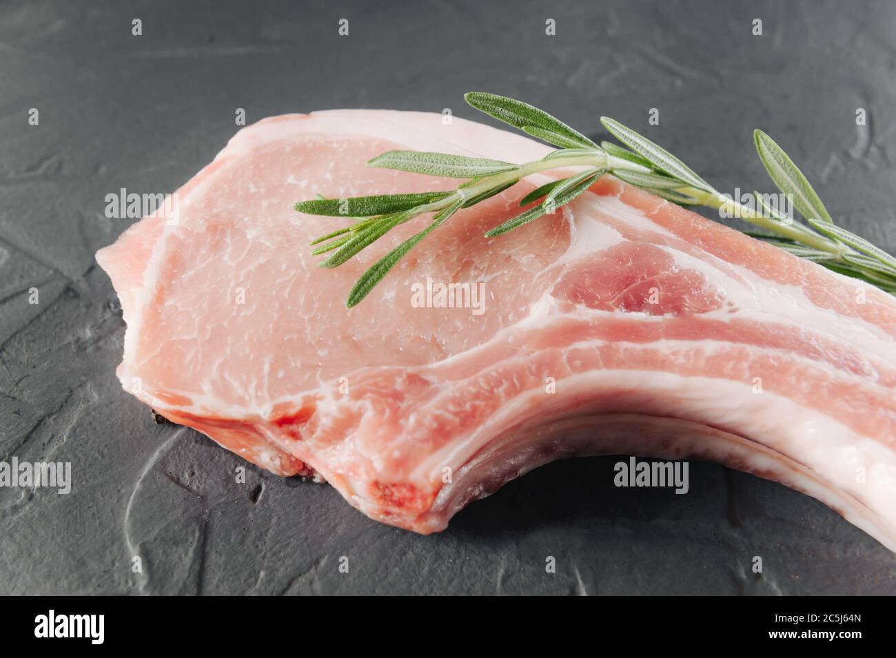 Fresh raw beef bone ribs with rosemary and spices on a dark blue ...