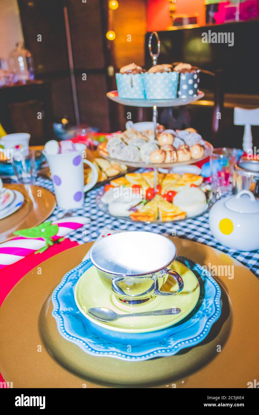 Colorful Tea party with table laid out fancy tea cups and saucers, with ...